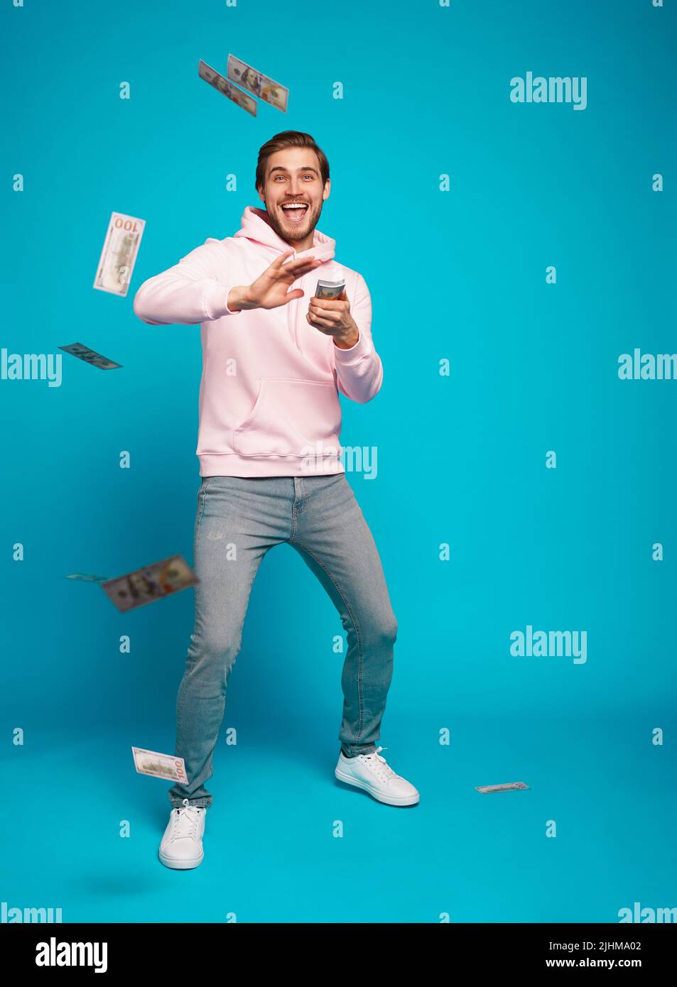 Portrait of a joyful young man holding money cash and celebrating ...