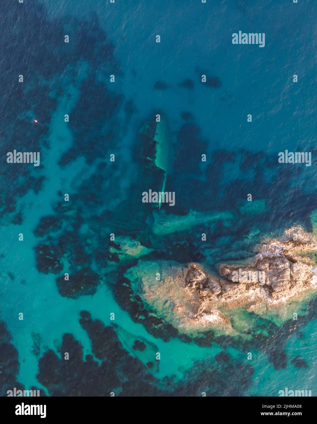 Aerial view of a sunken shipwreck near the rocks along the coast in ...