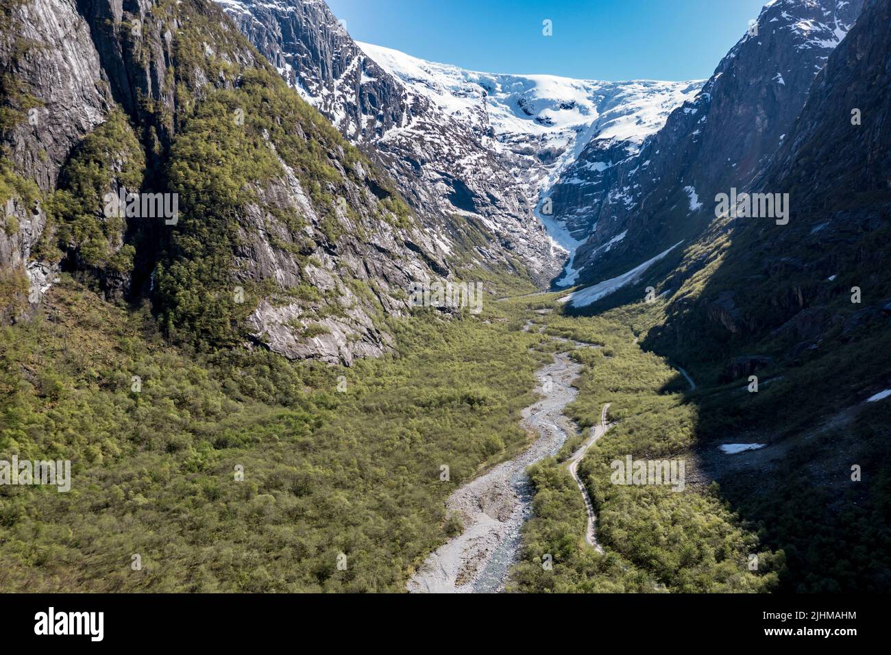 Aerial view over valley and gravel mountain road to glacier ...