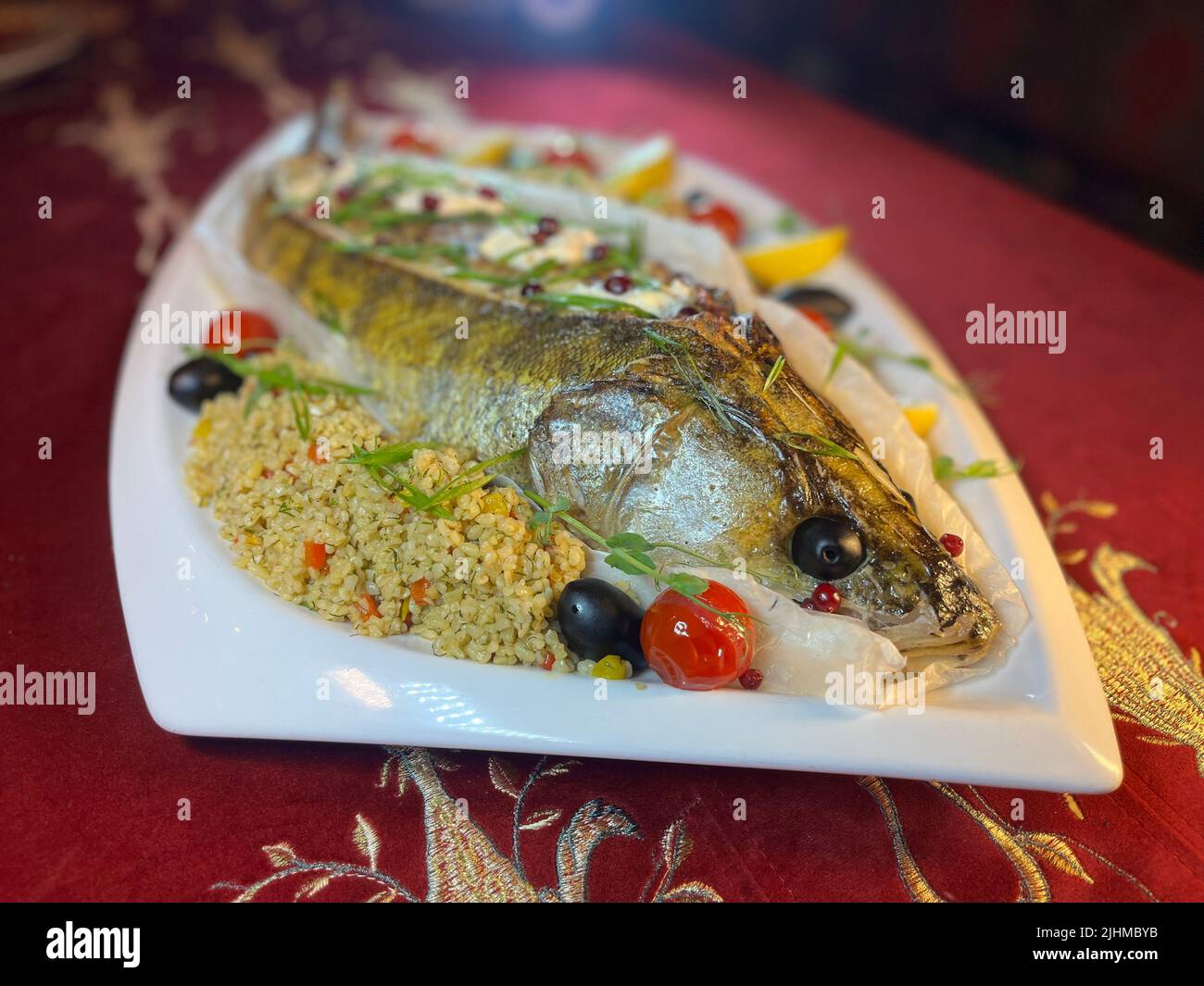 whole fish baked pike perch on a white platter is served in the ...