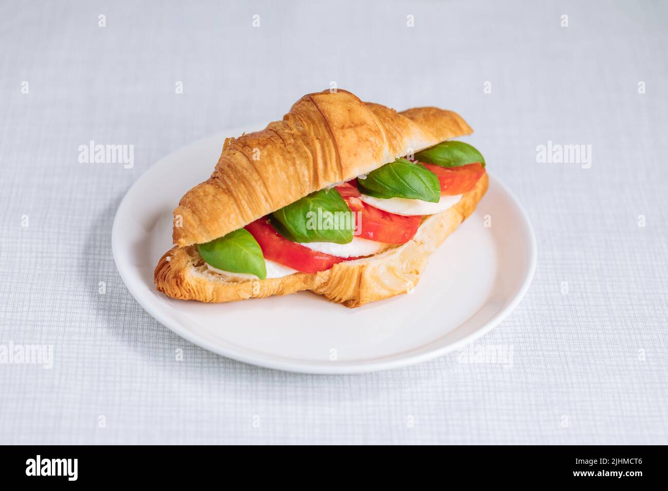 Croissant sandwich with basil, tomato and mozzarella cheese on white ...