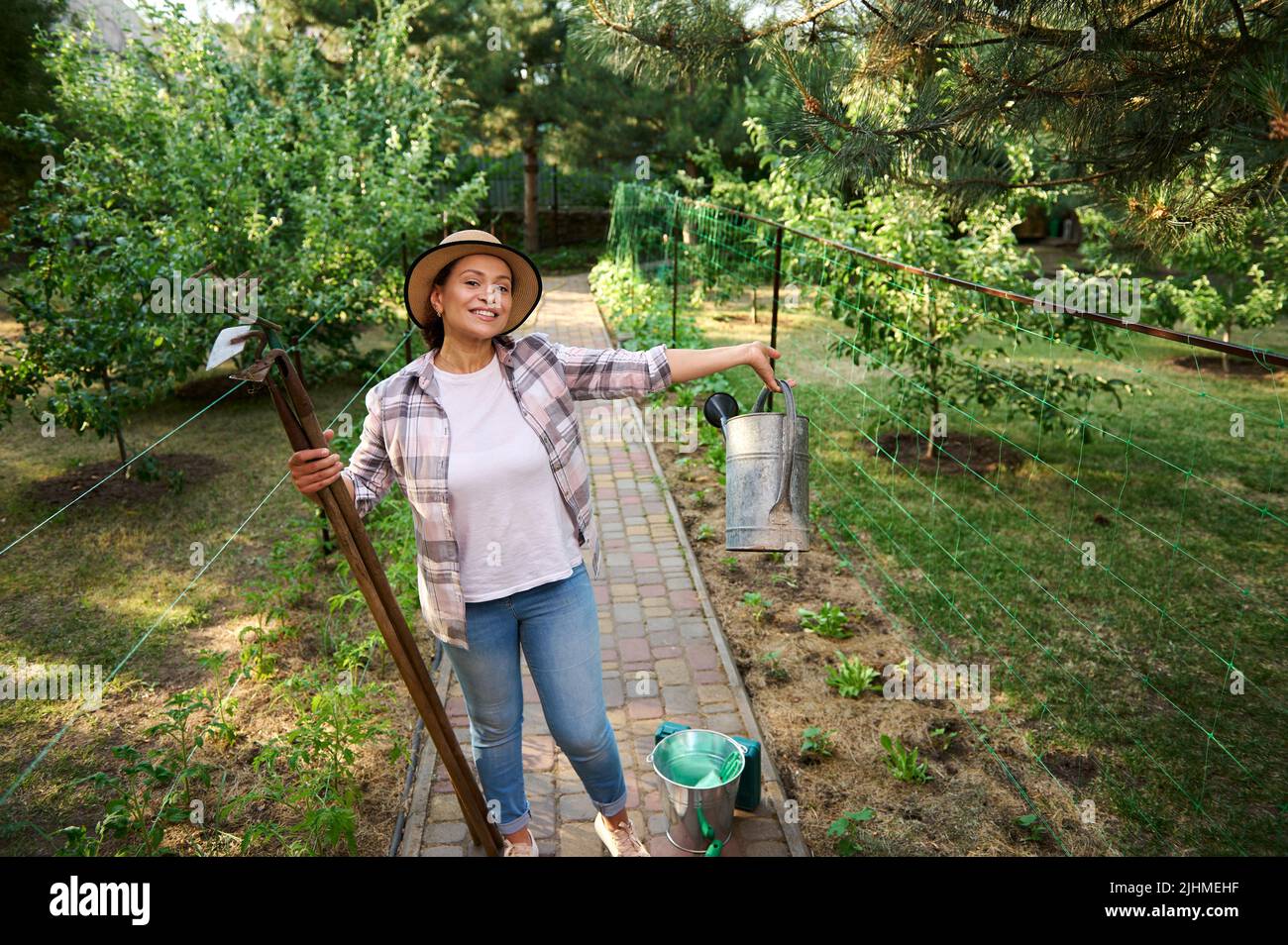 Portrait of happy successful female farmer enjoys gardening in eco farm ...