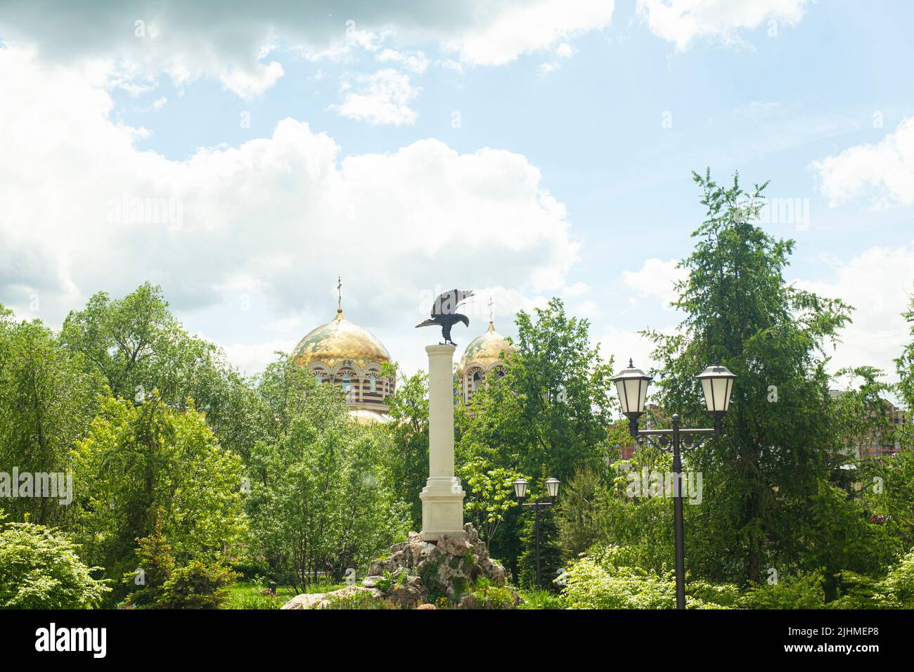 Eagle stone statue and Christian church with golden domes and cross in ...