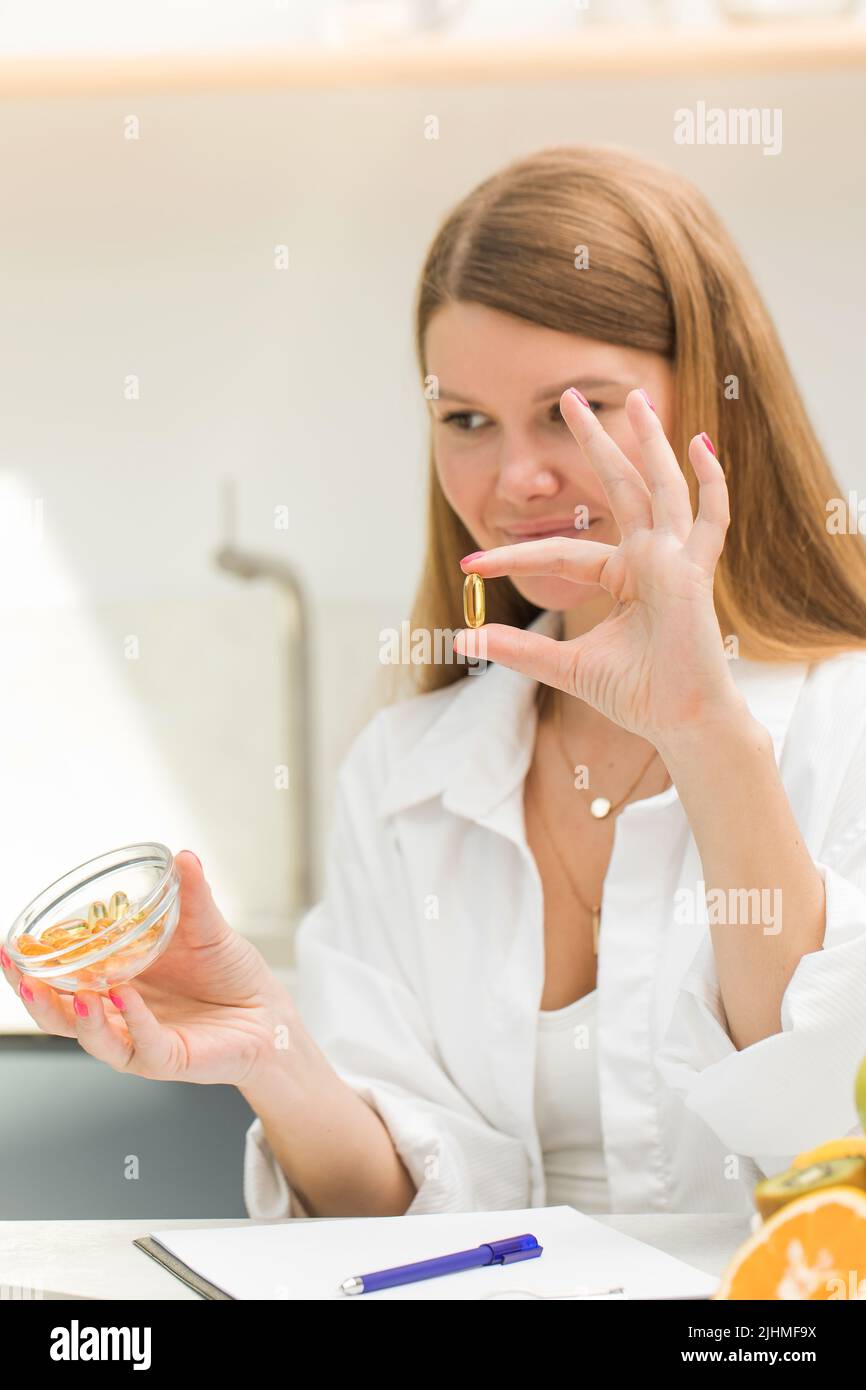 The doctor shows a large yellow capsule with vitamin D or omega 3 ...