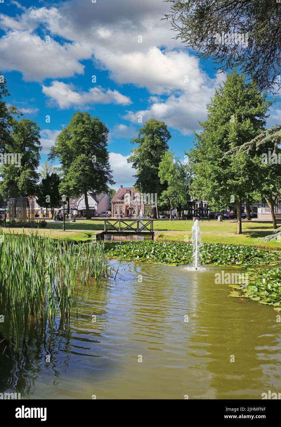 Beautiful idyllic green dutch town park, pond, wood bridge, blue summer ...