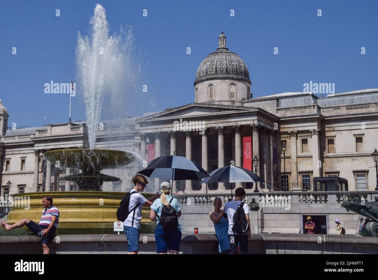 People shield themselves from the sun with umbrellas in Trafalgar ...