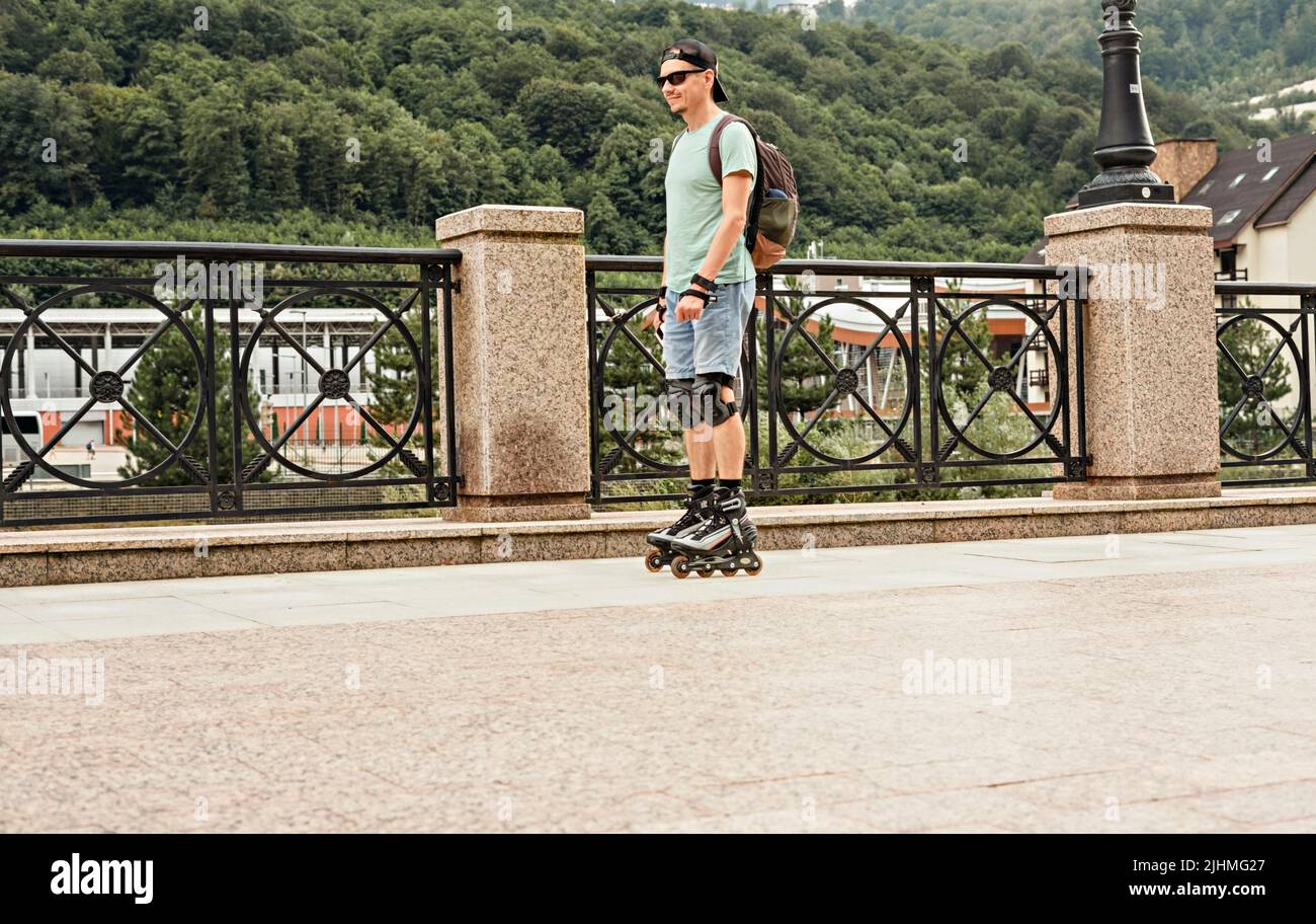 Young man in blue clothes in protective equipment riding on roller ...