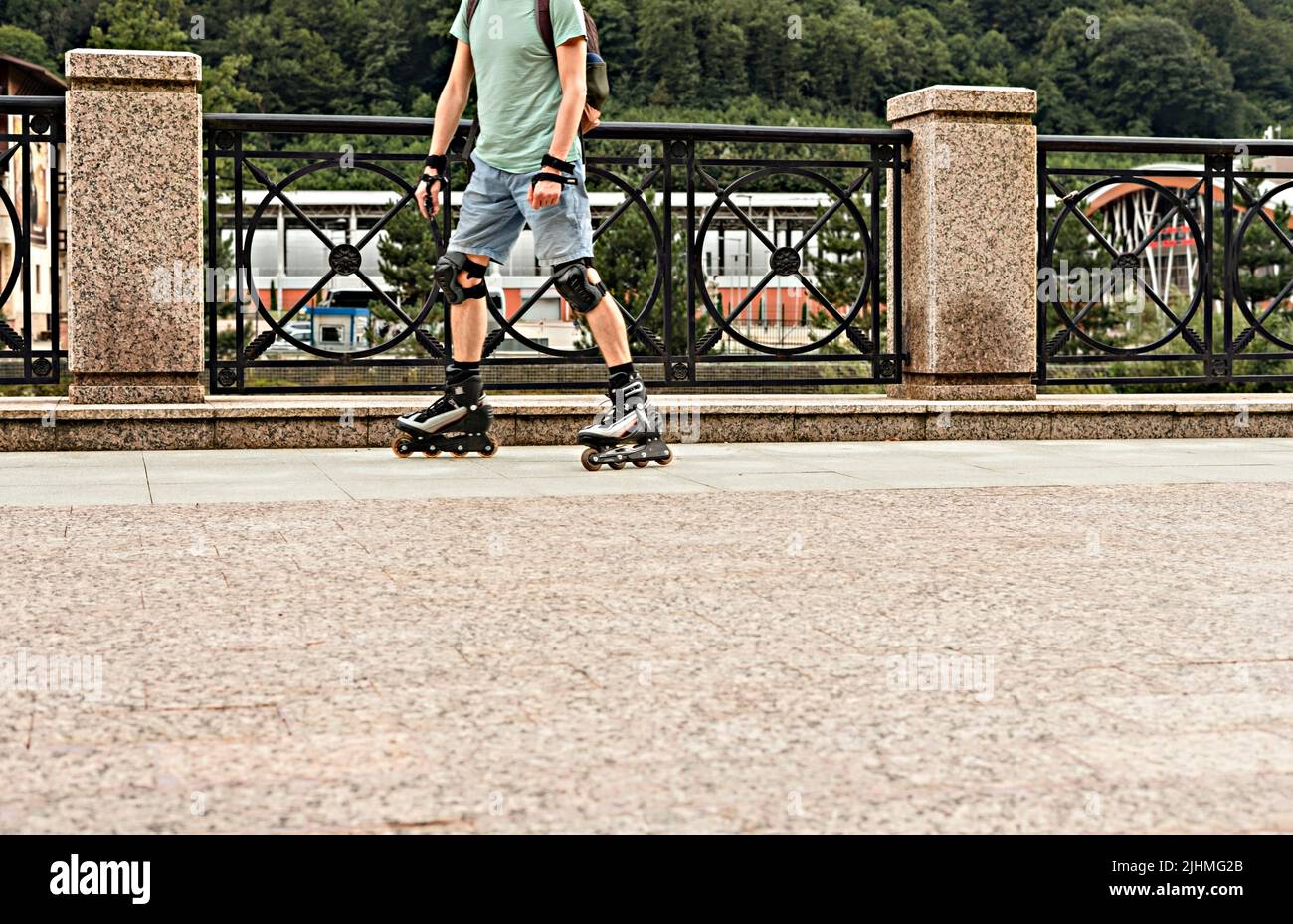 Young man in blue clothes in protective equipment riding on roller ...