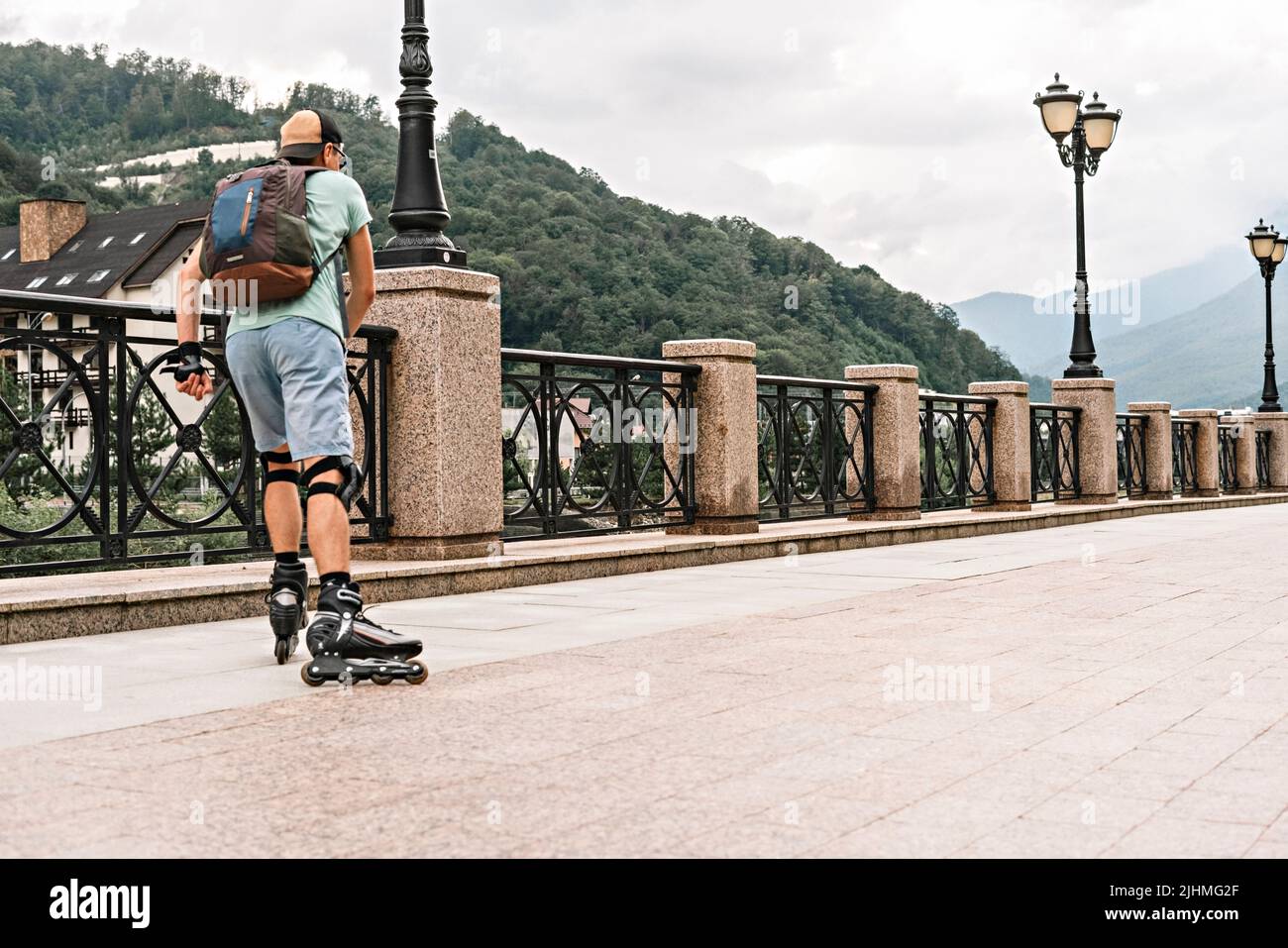 rear view of young man in blue clothes in protective equipment riding ...
