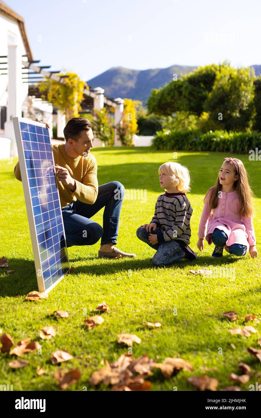Vertical image of caucasian father showing solar panel to children ...