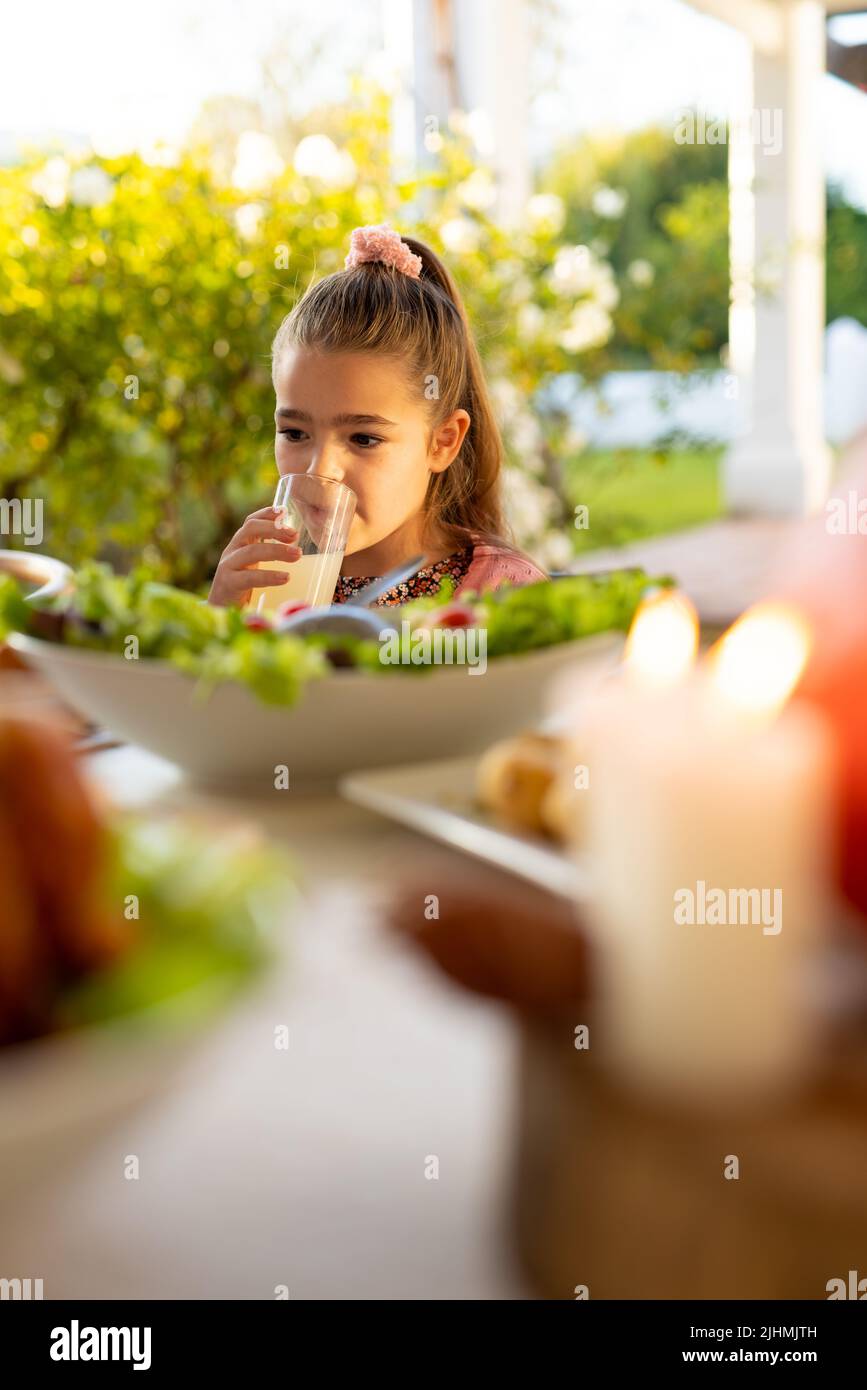 Vertical image of caucasian girl drinking juice during family dinner ...