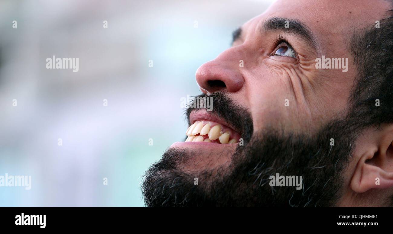Hopeful man in 40s opening eyes to sky with FAITH, close-up face eye ...