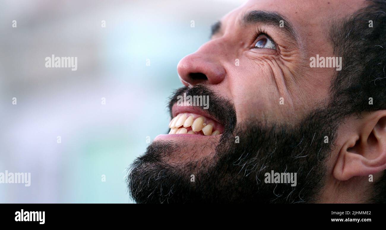 Hopeful man in 40s opening eyes to sky with FAITH, close-up face eye ...