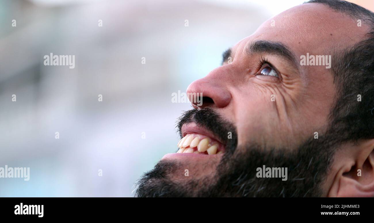 Hopeful man in 40s opening eyes to sky with FAITH, close-up face eye ...
