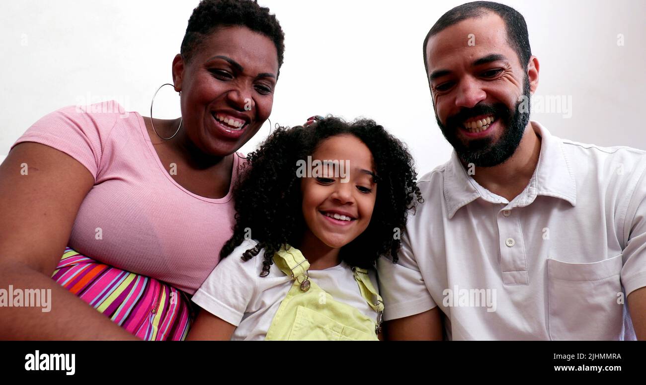 Interracial parents and mixed race child daughter looking at cellphone ...