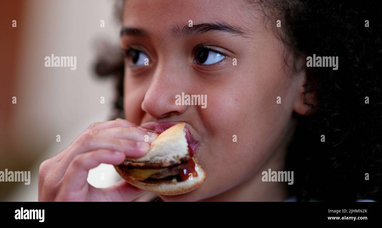 Little girl eating burger. Child taking a bite of hamburger Stock Photo ...