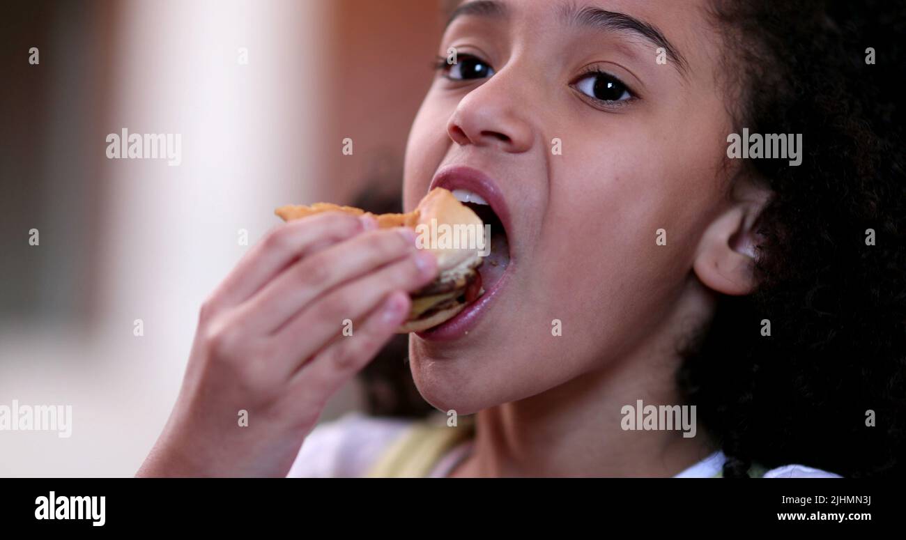 Little girl eating burger. Child taking a bite of hamburger Stock Photo ...
