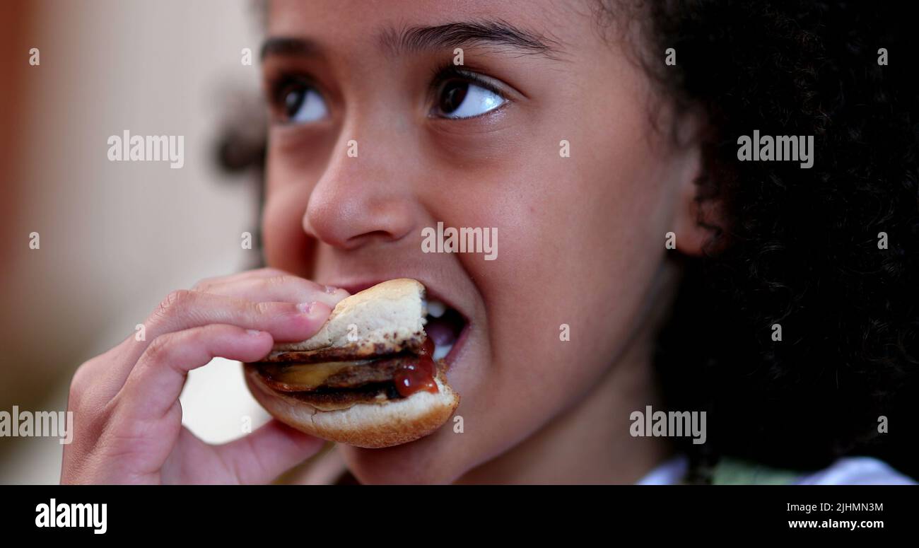 Little girl eating burger. Child taking a bite of hamburger Stock Photo ...