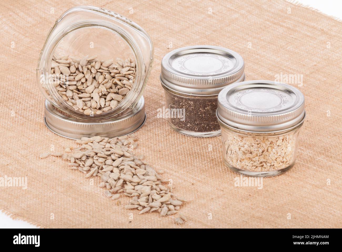 Three glass containers with different seeds: chia, sunflower seeds and ...