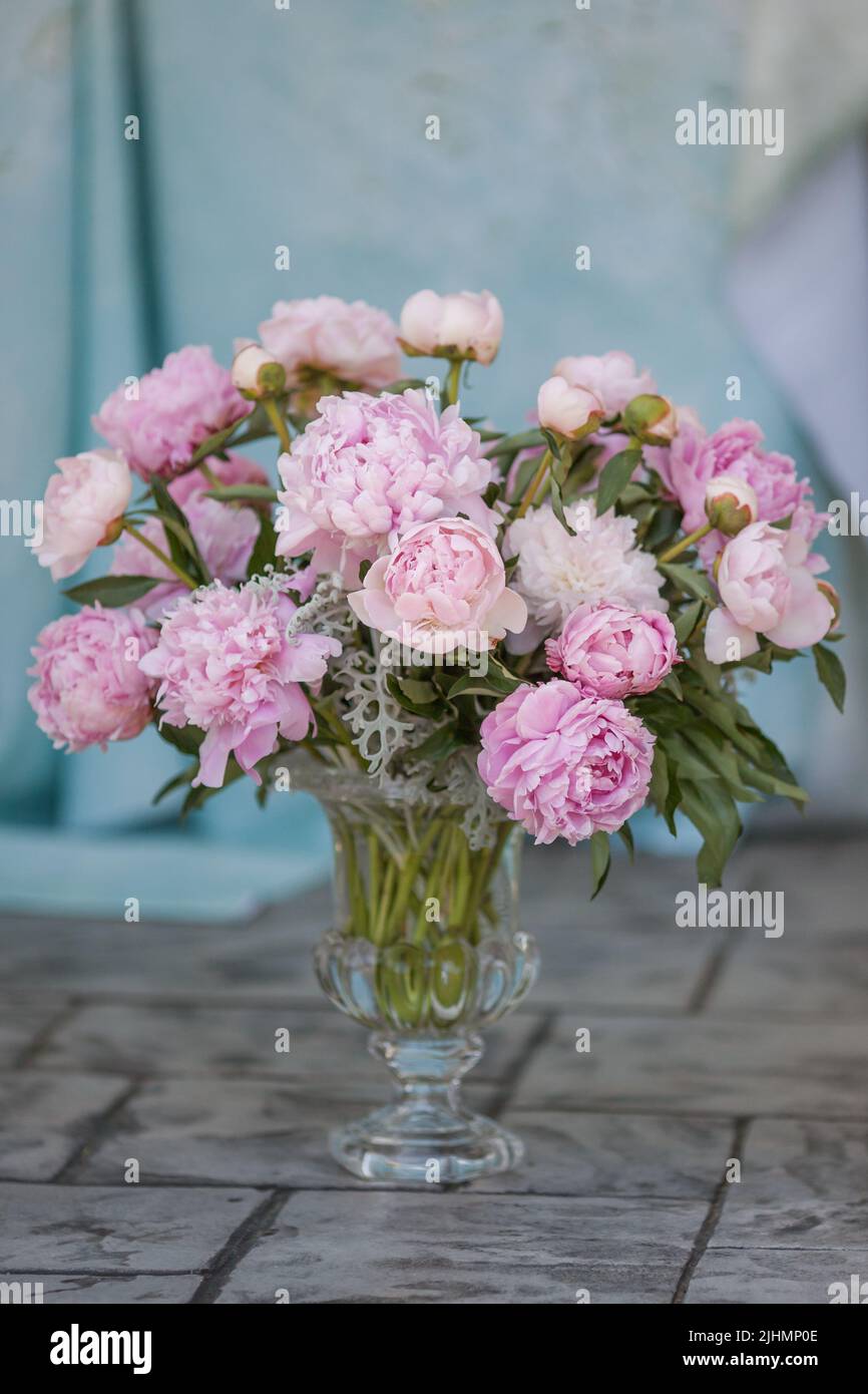 A bouquet of soft pink peonies sitting on a cement floor Stock Photo ...