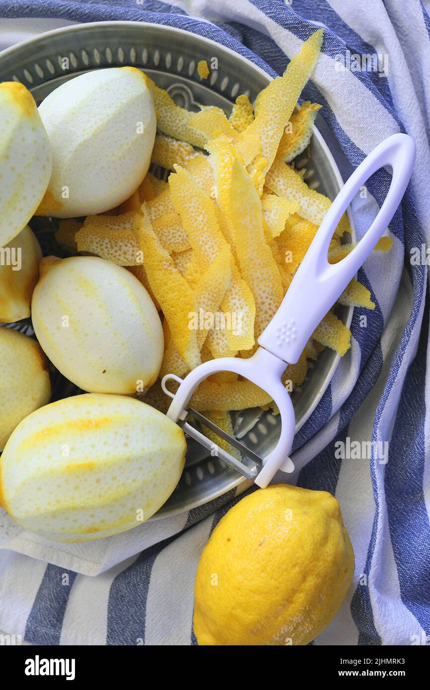 Lemon fruits and peeled strips for zest or making limoncello. Peeler, lemons and zest. Copy ...