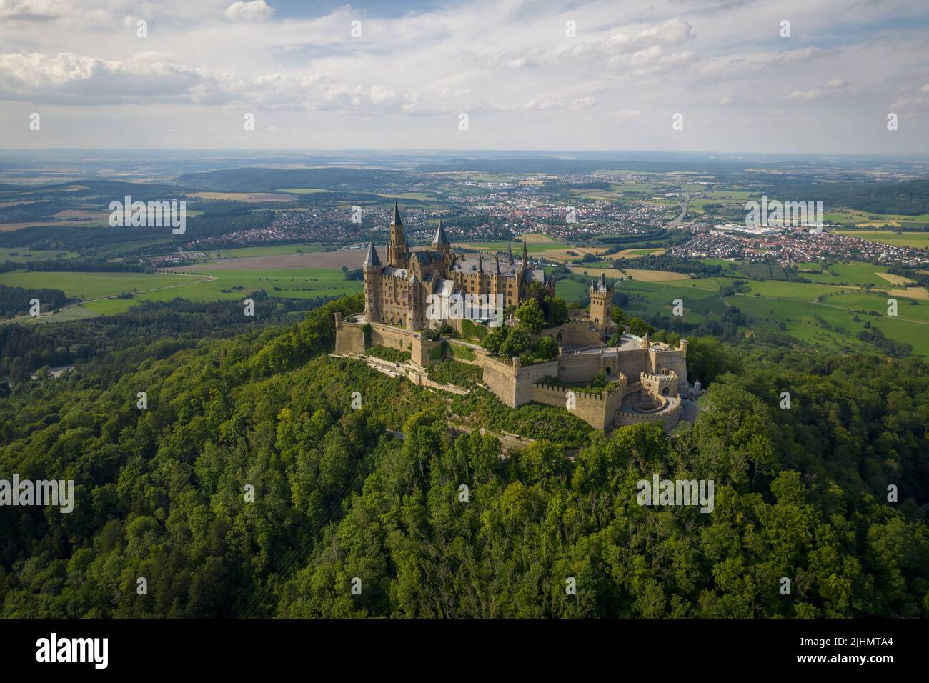 Drone shot of Hohenzollern Castle on forested mountain top in the ...