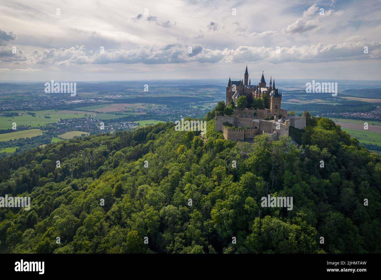 Drone shot of Hohenzollern Castle on forested mountain top in the ...