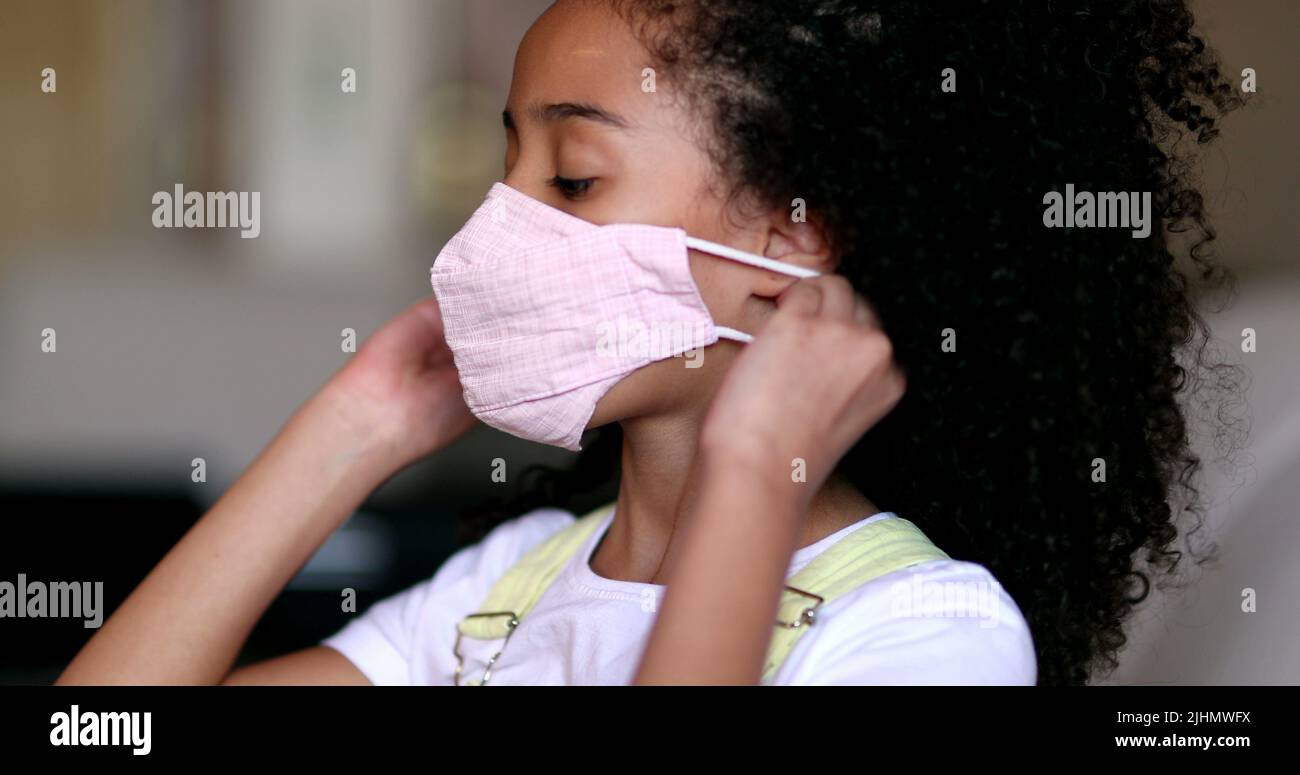 Little girl wearing covid-19 face mask. Portrait kid putting mask on ...
