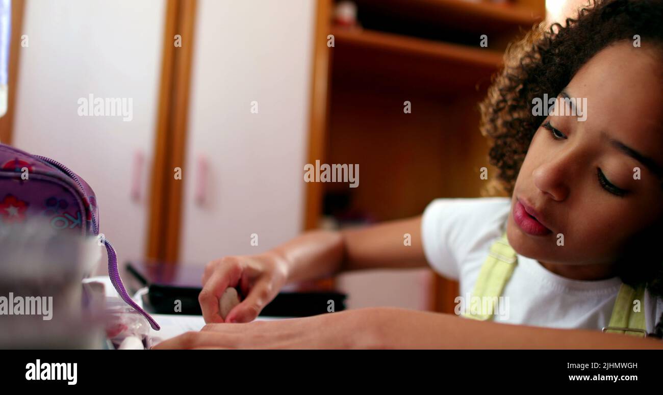 Little girl studying at home, mixed race child writing notes doing ...