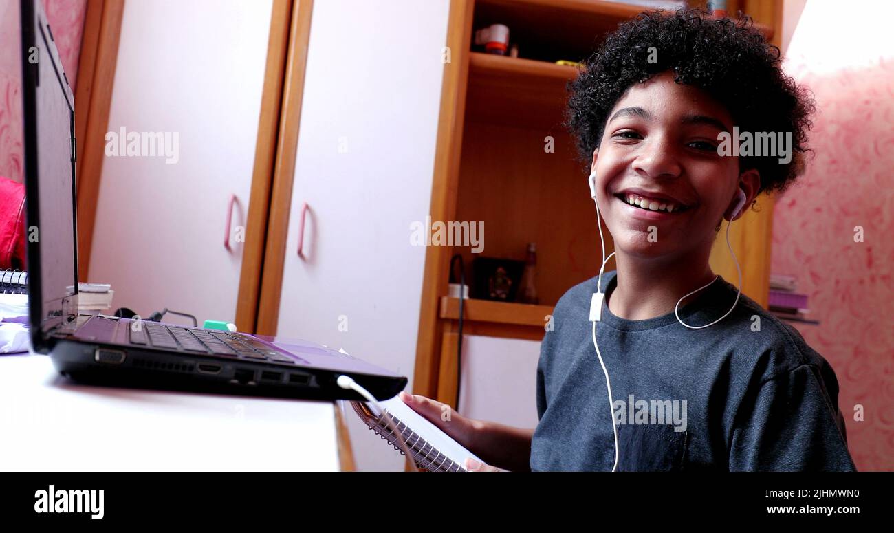 Mixed race boy writing notes on notepad at home doing homework Stock ...
