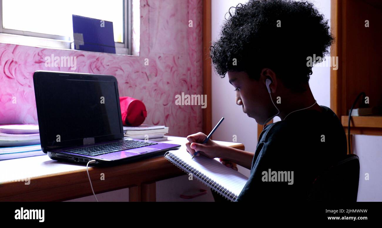 Mixed race boy writing notes on notepad at home doing homework Stock ...
