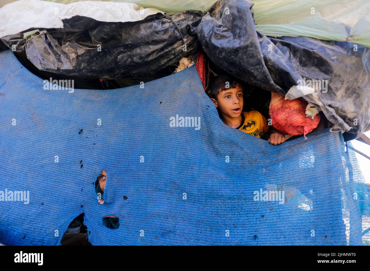 Palestinian refugees play inside their shelter on a hot day in the ...