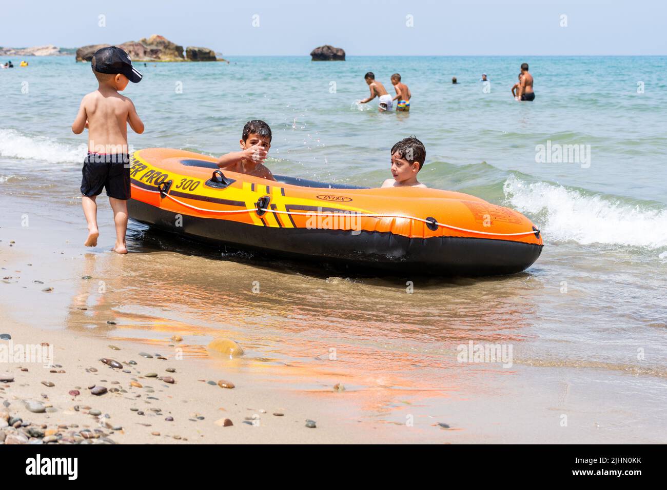 Young boys inside the inflatable boat on the beach. Summer vacation ...