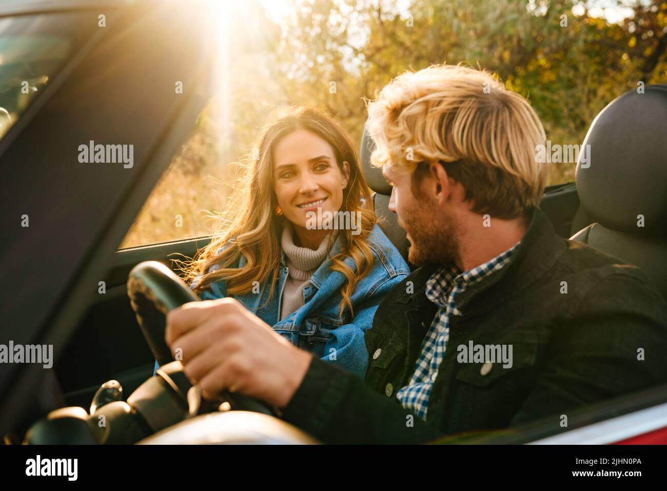 White mid couple smiling together while driving in car during trip ...
