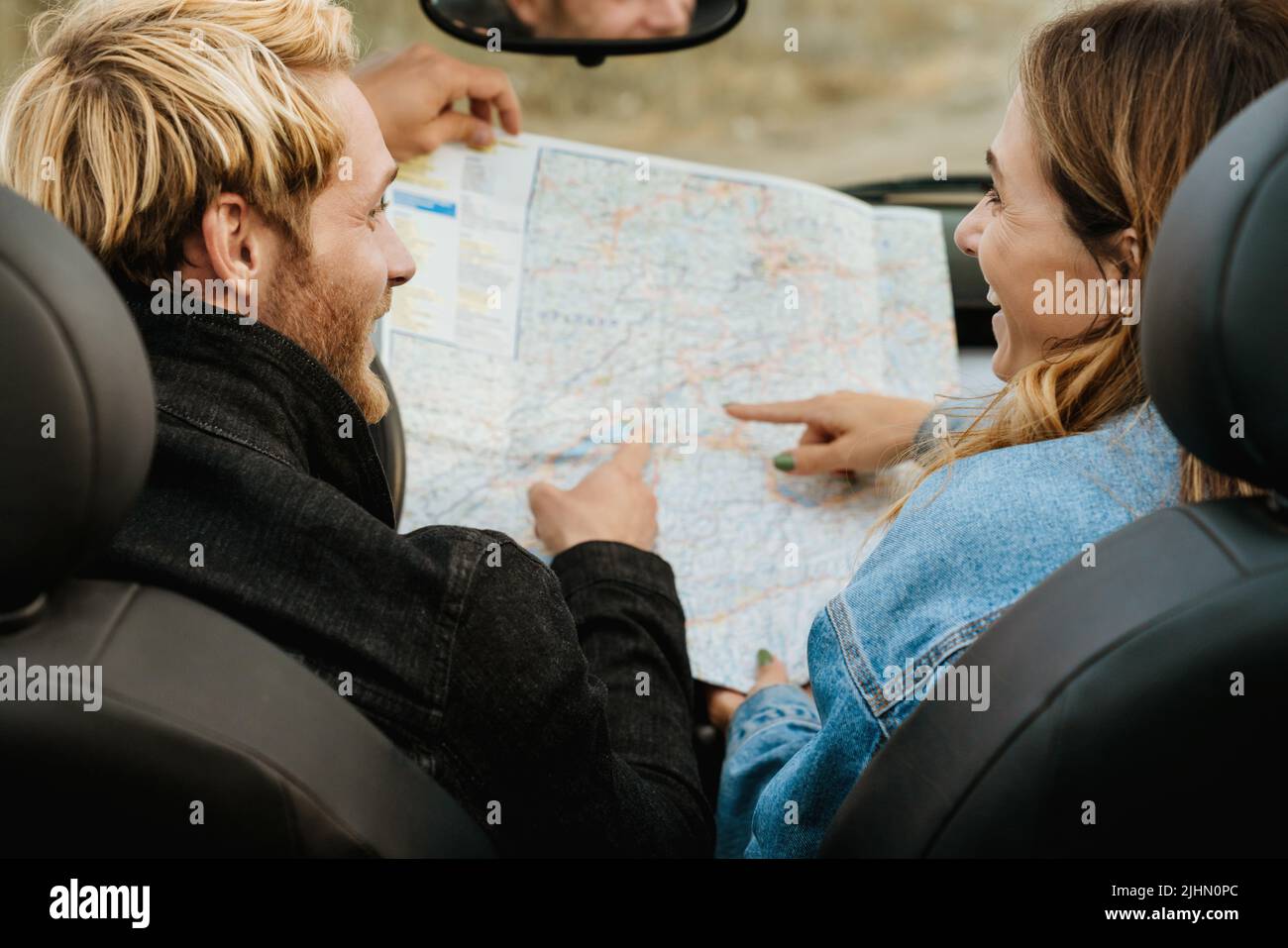 White mid couple smiling and examining map while sitting in car during ...