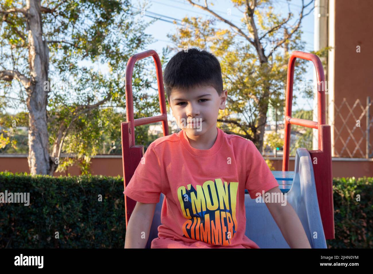 Portrait of cute boy playing on slide in beautiful sunny day, sunset in ...