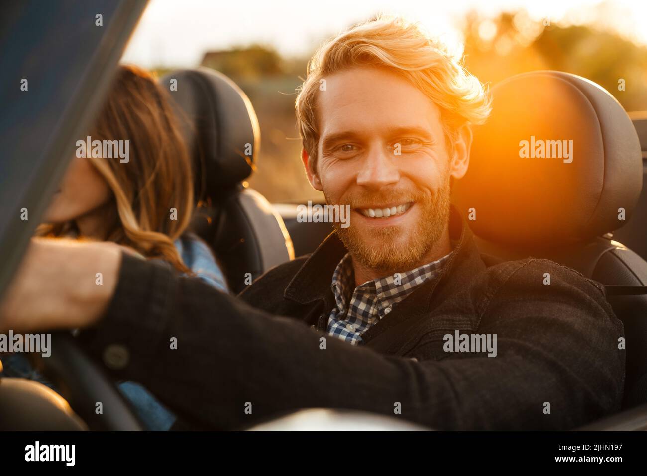 White mid couple smiling together while driving in car during trip ...