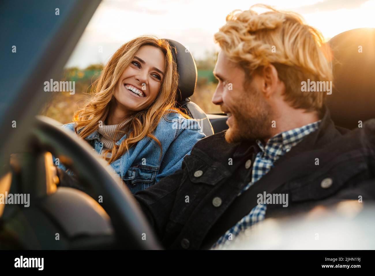 White mid couple smiling together while driving in car during trip ...