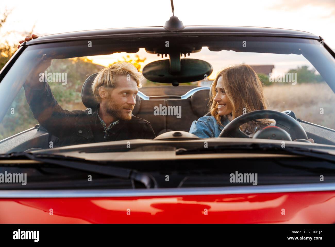 White mid couple smiling together while driving in car during trip ...