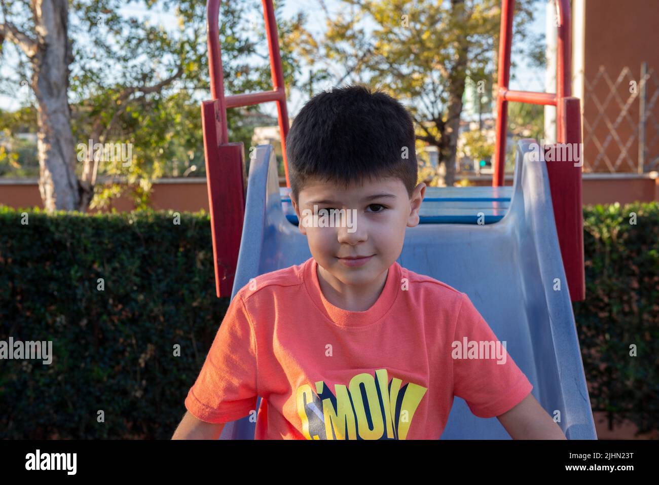 Portrait of cute boy playing on slide in beautiful sunny day, sunset in ...