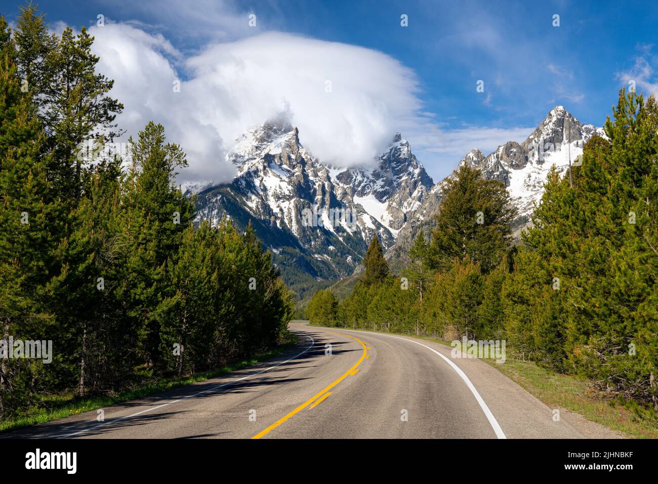 Highway curves towards snow-capped mountain peaks of the Teton Range ...