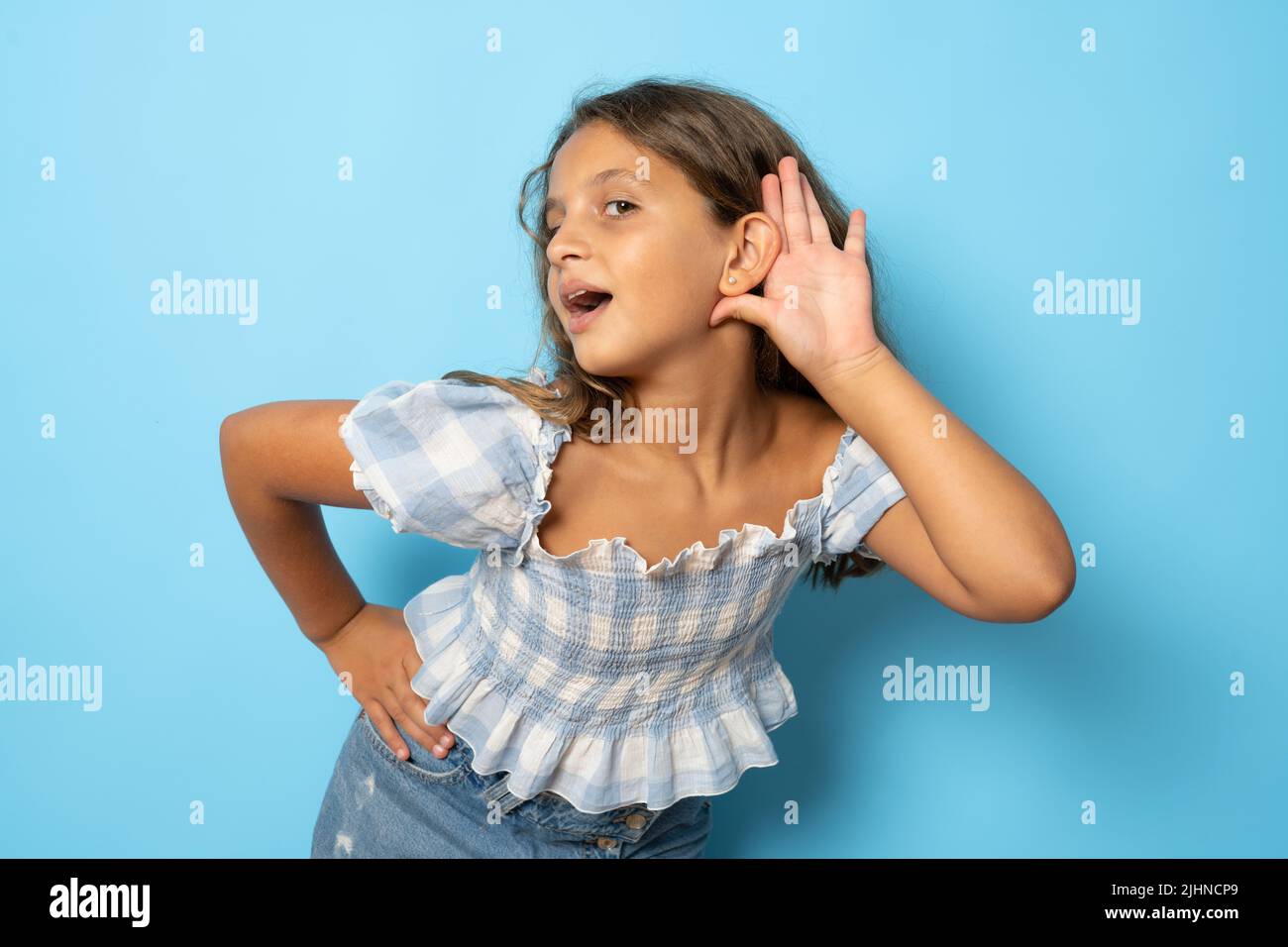 Little girl trying to hear you overhear listening intently isolated on blue background child ...