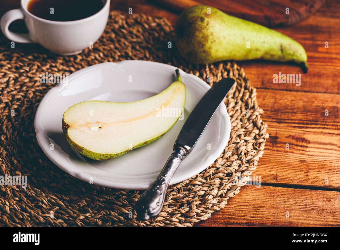 Halved Green Pear on White Plate with Knife Stock Photo - Alamy