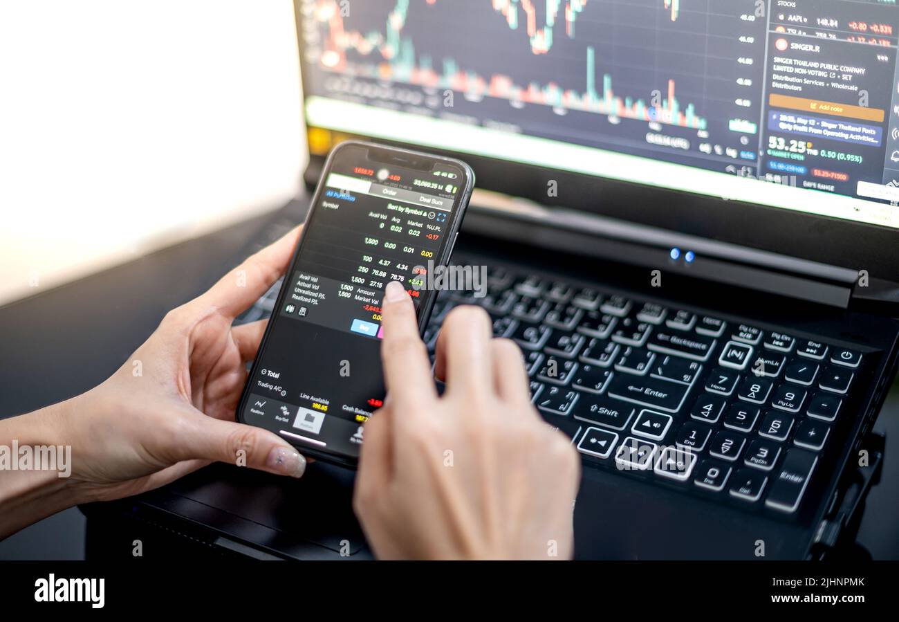 Female trader investor broker analyst holding a smartphone in hand ...