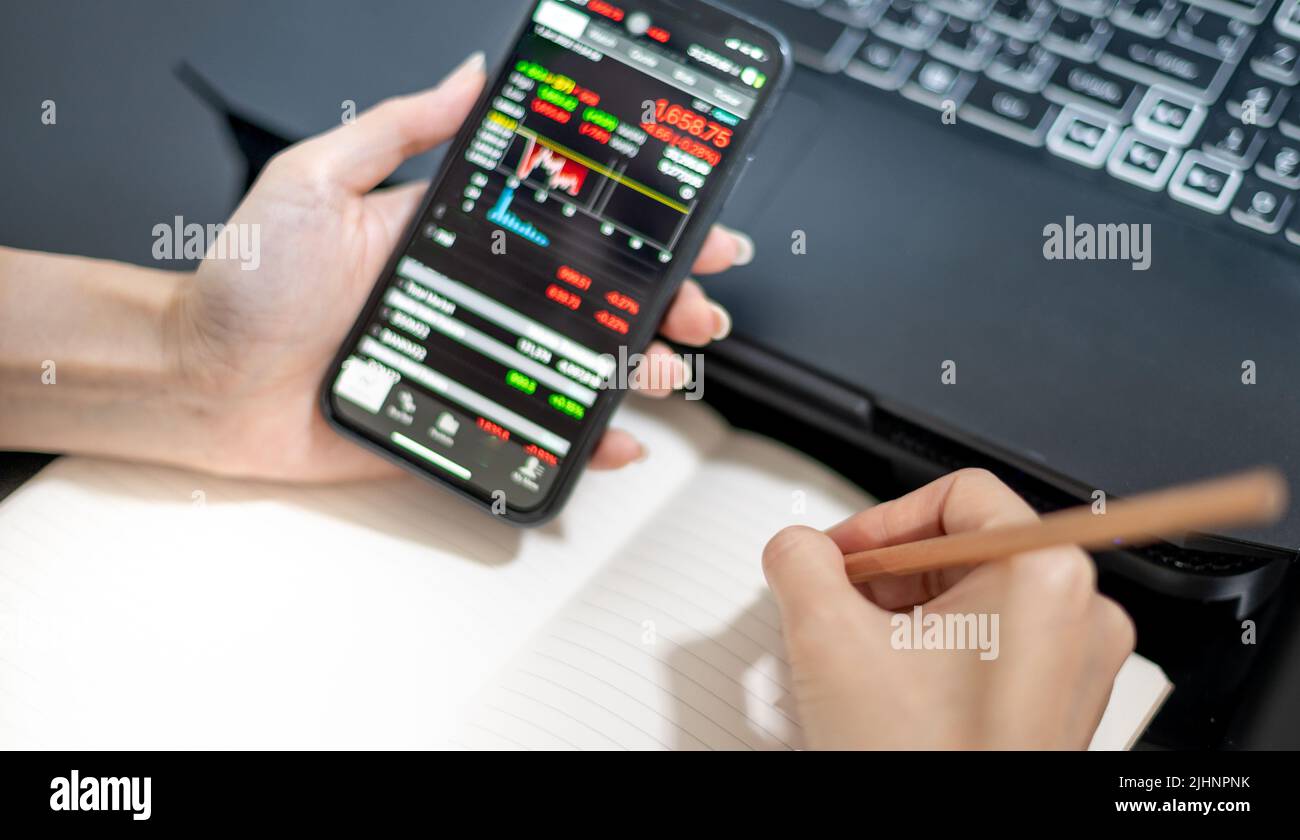 Female trader investor broker analyst holding a smartphone in hand ...