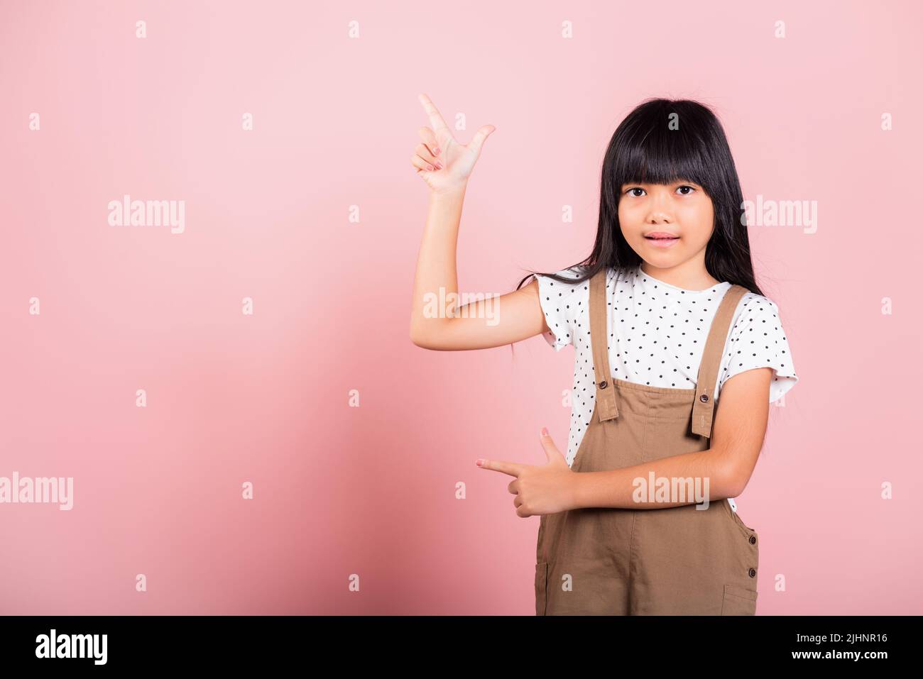 Asian little kid 10 years old point with index finger up at studio shot ...