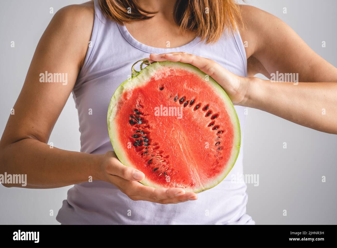 Half of watermelon in hands and midsection of unknown caucasian woman ...