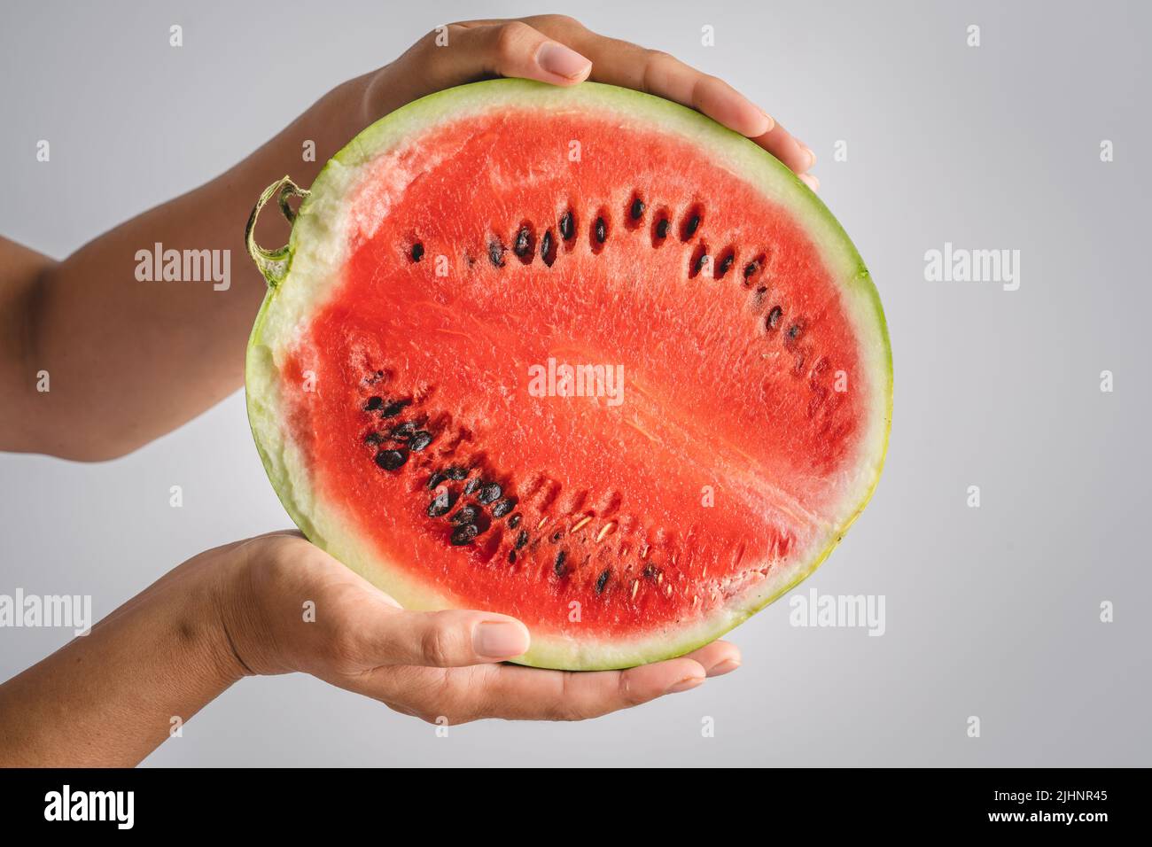 Half of watermelon in hands of unknown caucasian woman holding it in ...