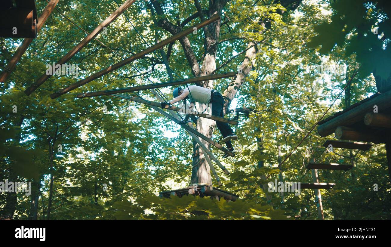 A man crossing rope construction in the forest - extreme attraction ...