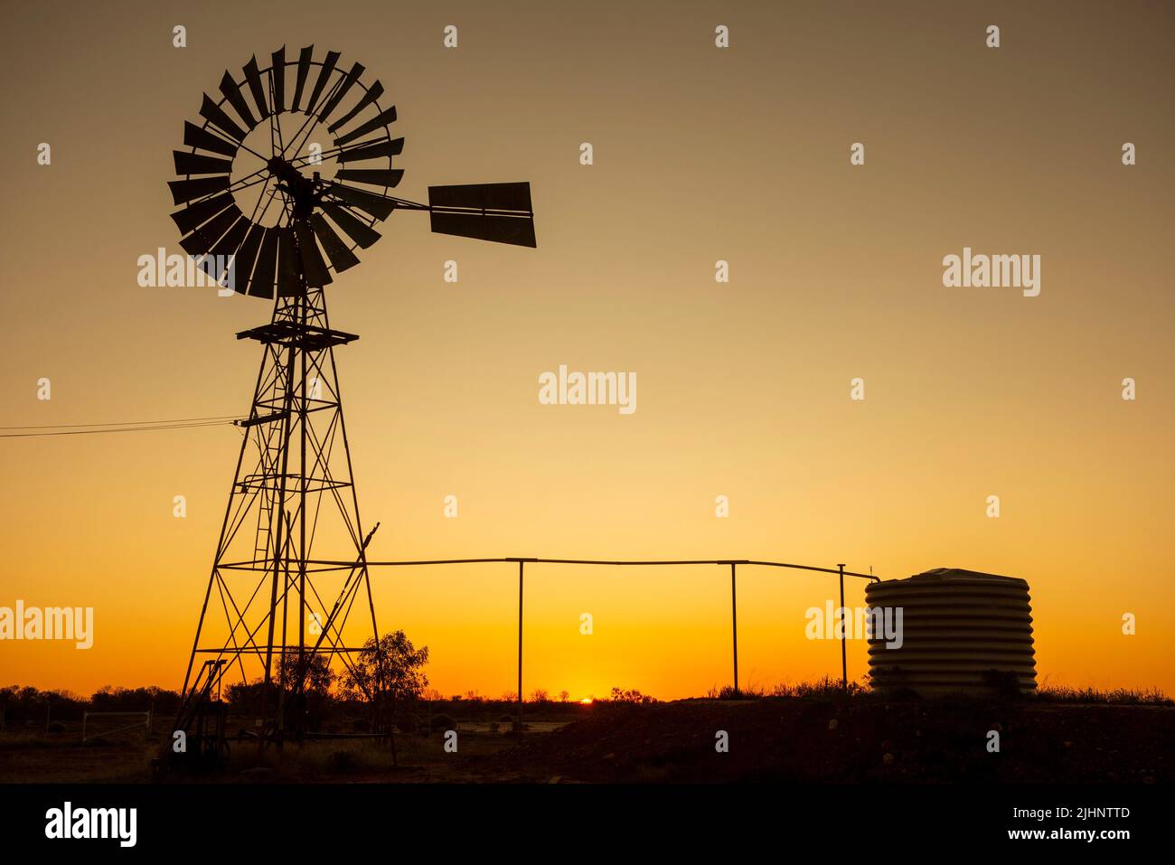 Sunset in outback Queensland with a water tank and windmill Stock Photo ...